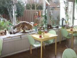Uma área de refeições com mesa e cadeiras, um radiador e uma janela com vista para um jardim.