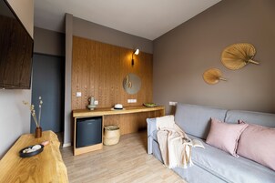 Uma sala de estar moderna com uma parede de destaque em madeira, um sofá cinza e uma pequena mesa de madeira com uma tigela e um chapéu.