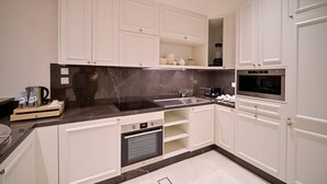 Uma cozinha moderna com armários brancos, bancada preta e eletrodomésticos embutidos, incluindo micro-ondas e forno.