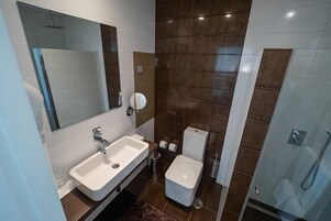 Casa de banho moderna com lavatório branco, sanita e zona de duche.