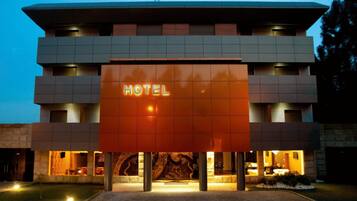 Um hotel moderno com um grande letreiro 'HOTEL', vários andares e uma entrada bem iluminada.