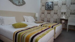 Quarto de hotel com duas camas, uma mesa e uma cadeira.