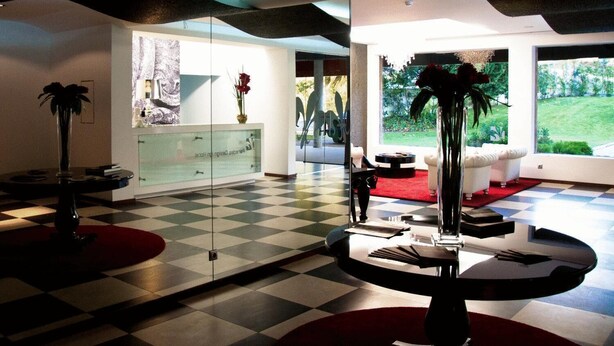 Uma sala de estar moderna com piso quadriculado, divisória de vidro e vista para o exterior.