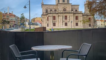 Uma área de estar ao ar livre com uma mesa redonda e duas cadeiras, um edifício grande com uma cúpula ao fundo e um céu limpo.