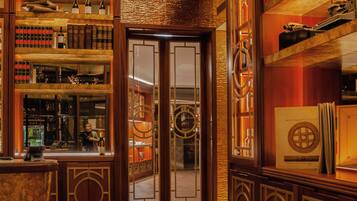 Um hall amplo com piso de madeira, um balcão de recepção e uma grande porta de vidro que dá para um espaço de bar.