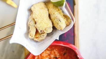 Uma bandeja com itens empanados e uma tigela de molho.