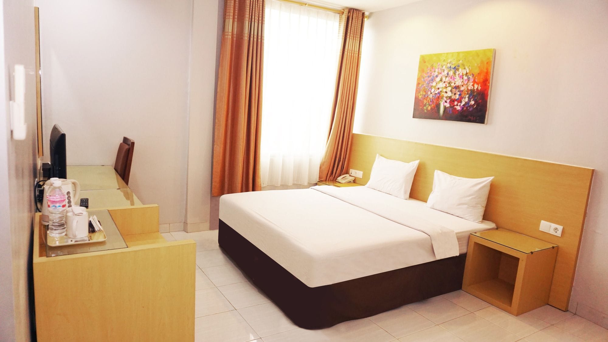 Quarto de hotel com cama, mesa de cabeceira e escrivaninha com cadeira.