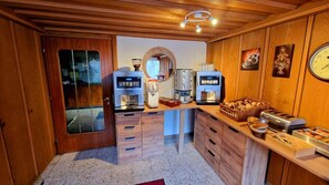 Uma cozinha compacta com armários de madeira, máquina de café, micro-ondas e torradeira.