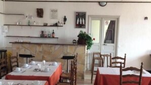 Uma sala de jantar com mesas postas, cadeiras, um bar e uma porta com um aviso.