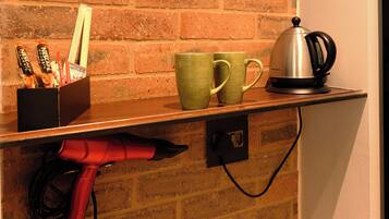 Uma bancada de cozinha com uma cafeteira, duas canecas e uma caixa de utensílios.