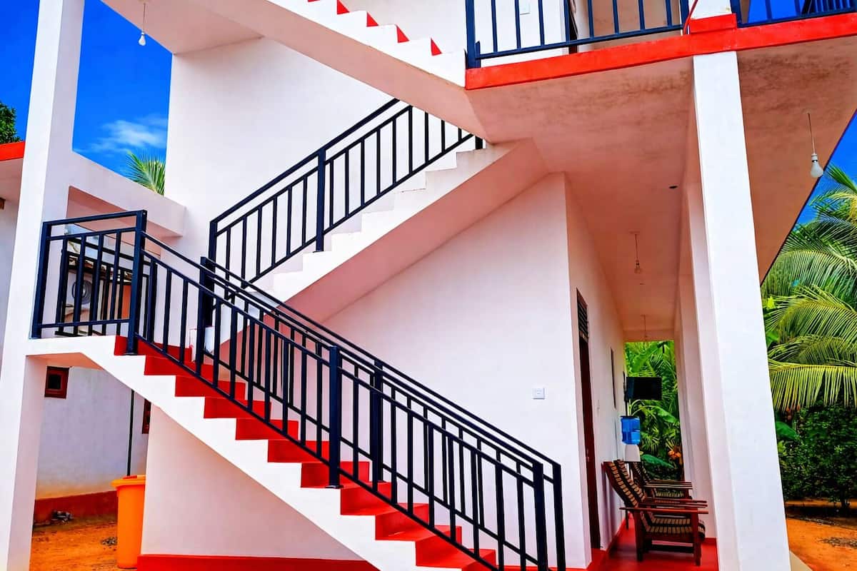 Um edifício com vários andares, escada e área externa com mesas e cadeiras.