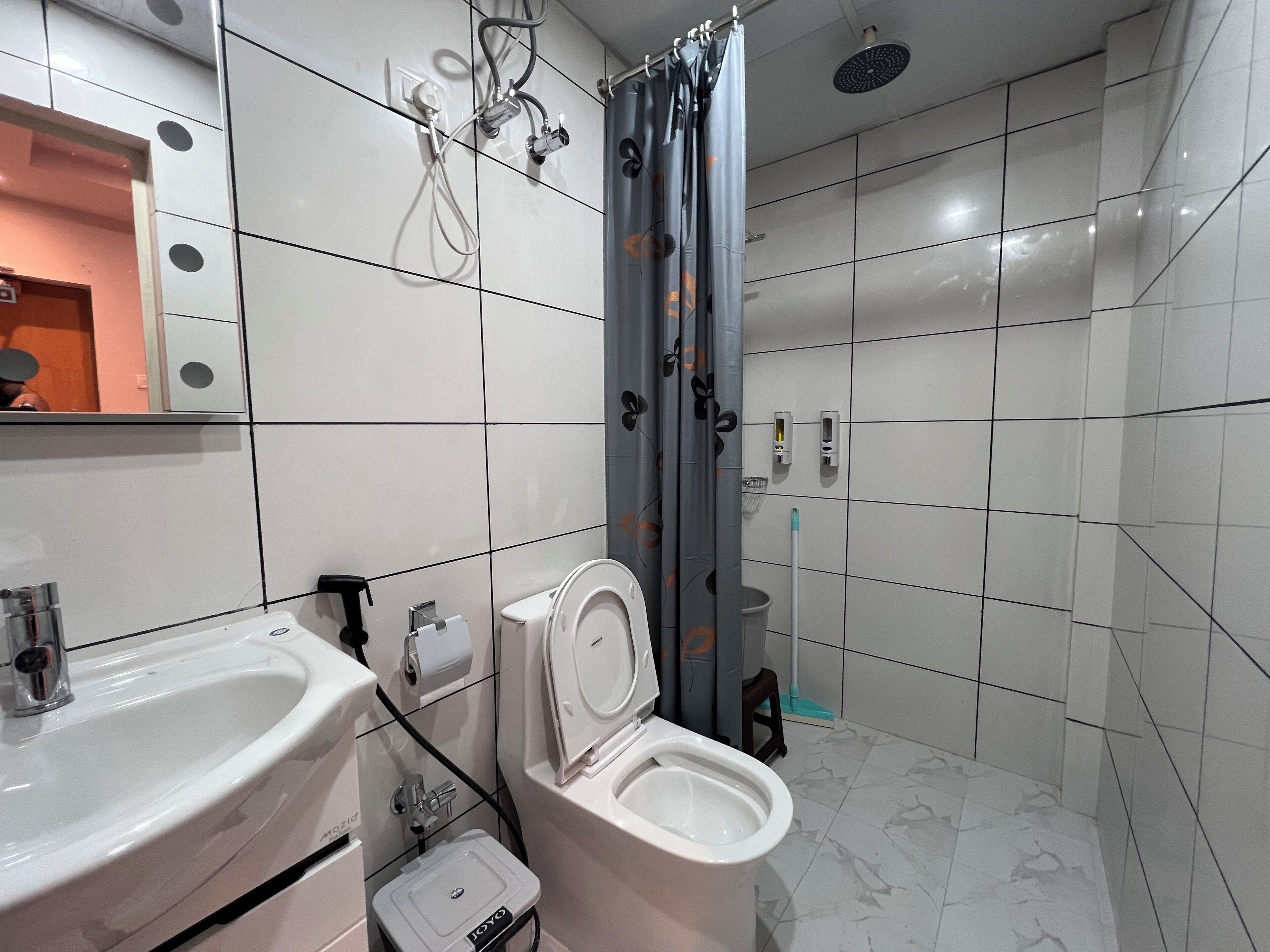 Uma casa de banho moderna com sanita, lavatório e chuveiro.