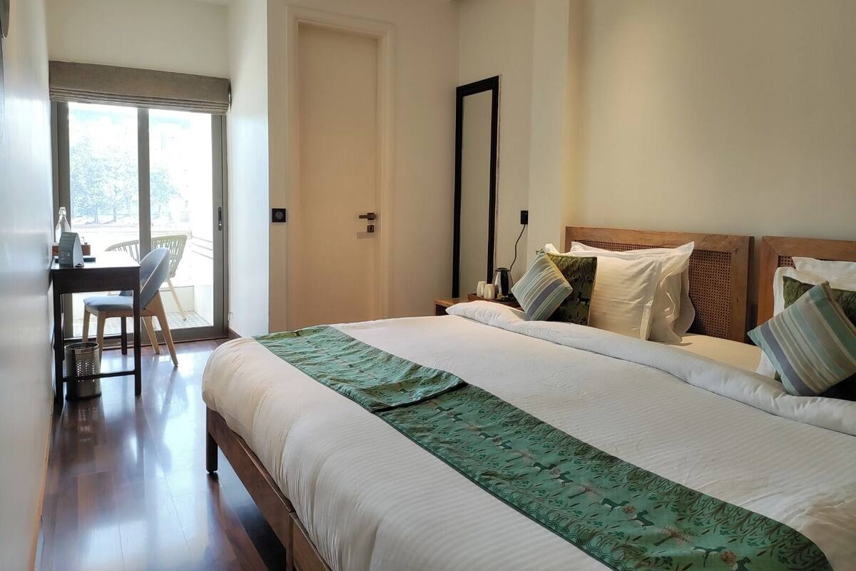 Quarto de hotel com uma cama grande, uma escrivaninha com cadeira, um espelho e vista através de uma porta.