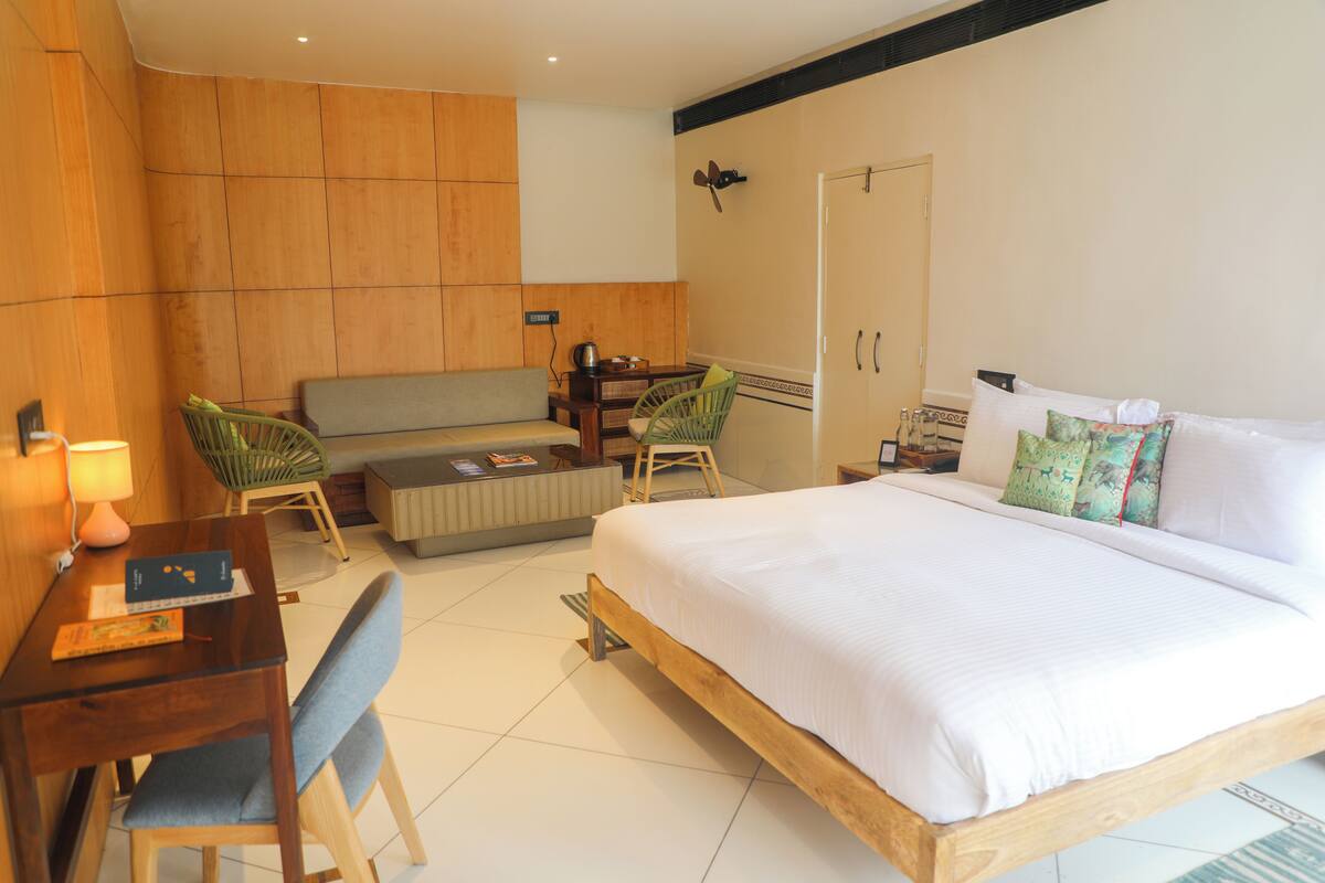 Quarto de hotel com cama, escrivaninha, cadeira, sofá e guarda-roupa.