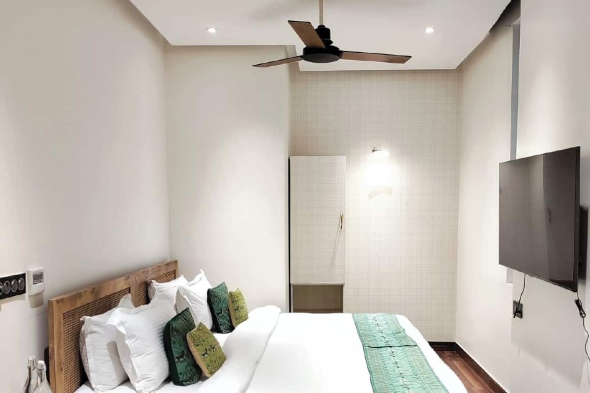 Quarto com cama, cabeceira de madeira, mesa de cabeceira e ventilador de teto.