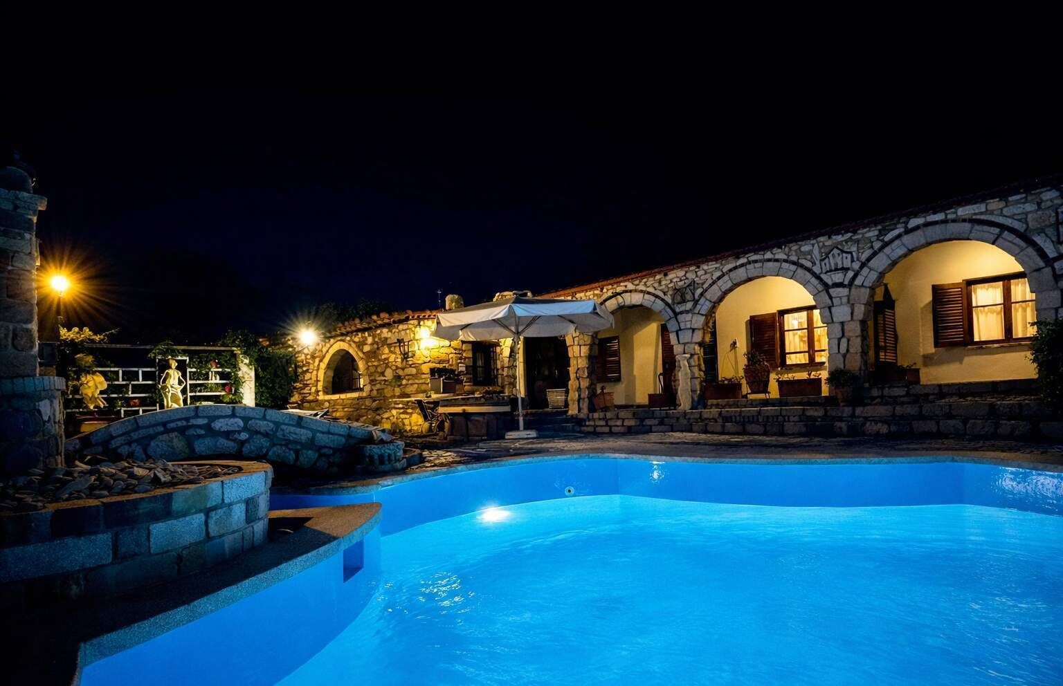 Piscina com arquitetura em pedra e área de estar ao ar livre.