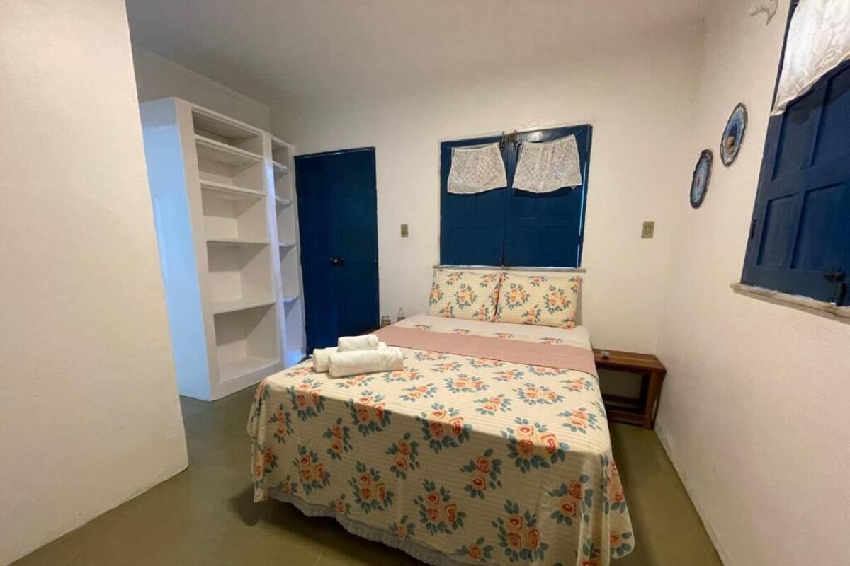Quarto com cama, guarda-roupa e janela com cortinas.