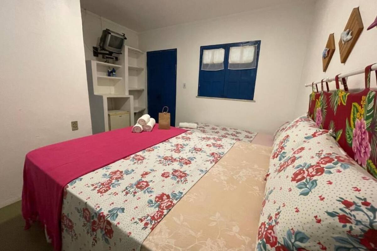 Quarto com cama, escrivaninha, cadeira, guarda-roupa e janela.