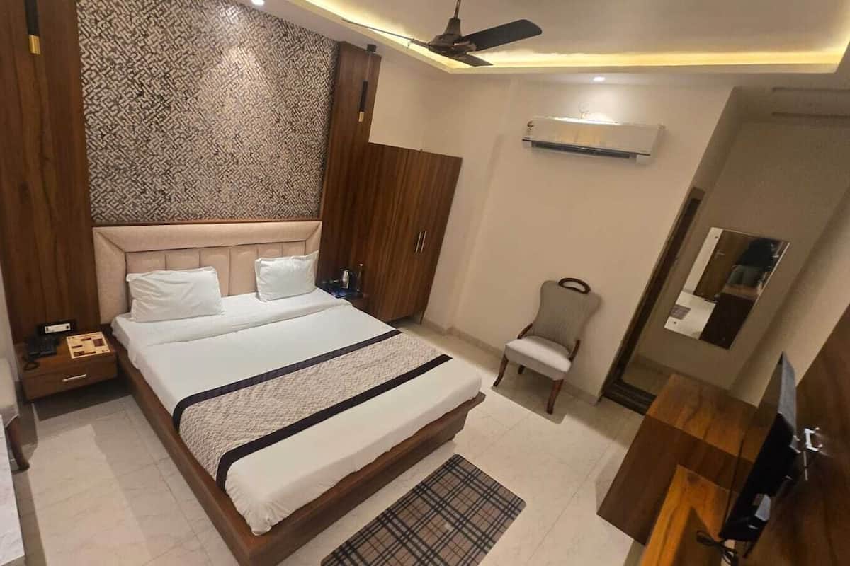 Quarto de hotel com uma cama grande, mesa de cabeceira, cadeira, escrivaninha e guarda-roupa.