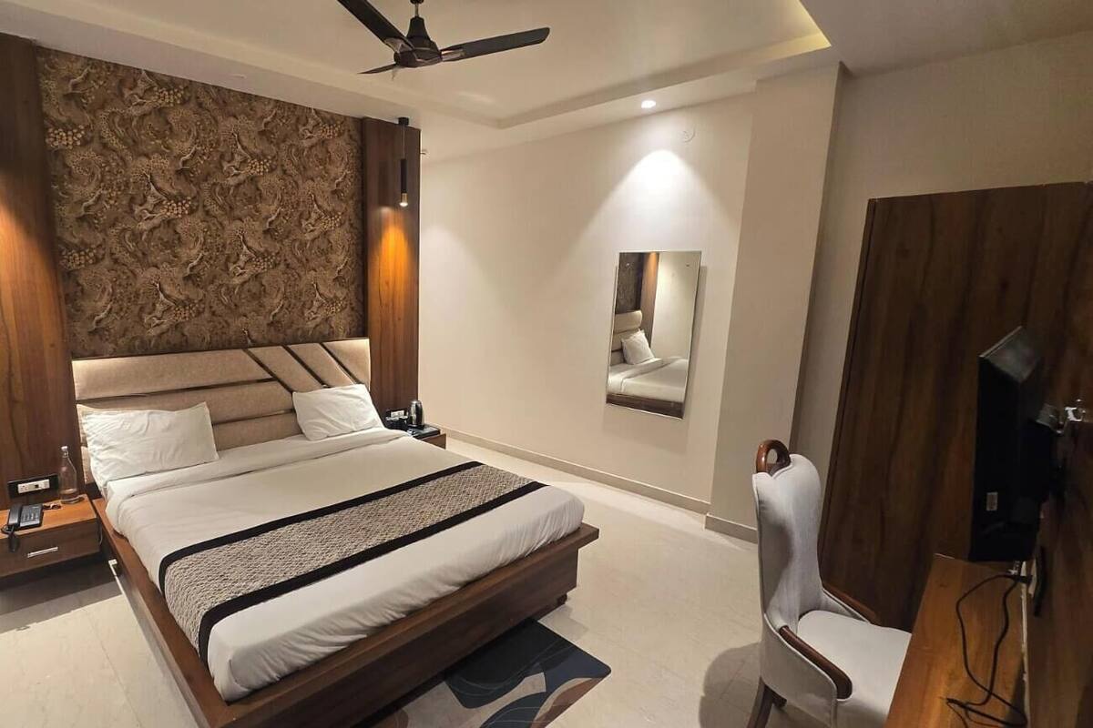 Quarto moderno com uma cama grande, um ventilador de teto, uma mesa de cabeceira, uma cadeira e um espelho na parede.