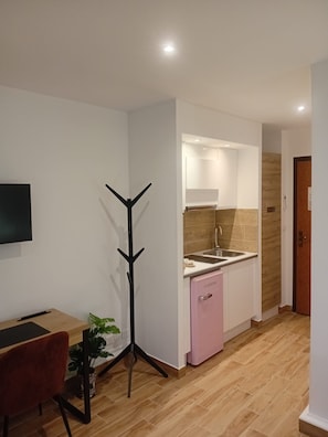 Cozinha compacta com pia, lava-louças rosa e piso de madeira.
