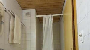 Um banheiro pequeno com chuveiro, pia e vaso sanitário.