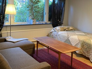 Quarto aconchegante com cama, sofá, mesa e janela com cortinas.