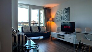 Uma sala de estar moderna com sofá, televisão e área de jantar.