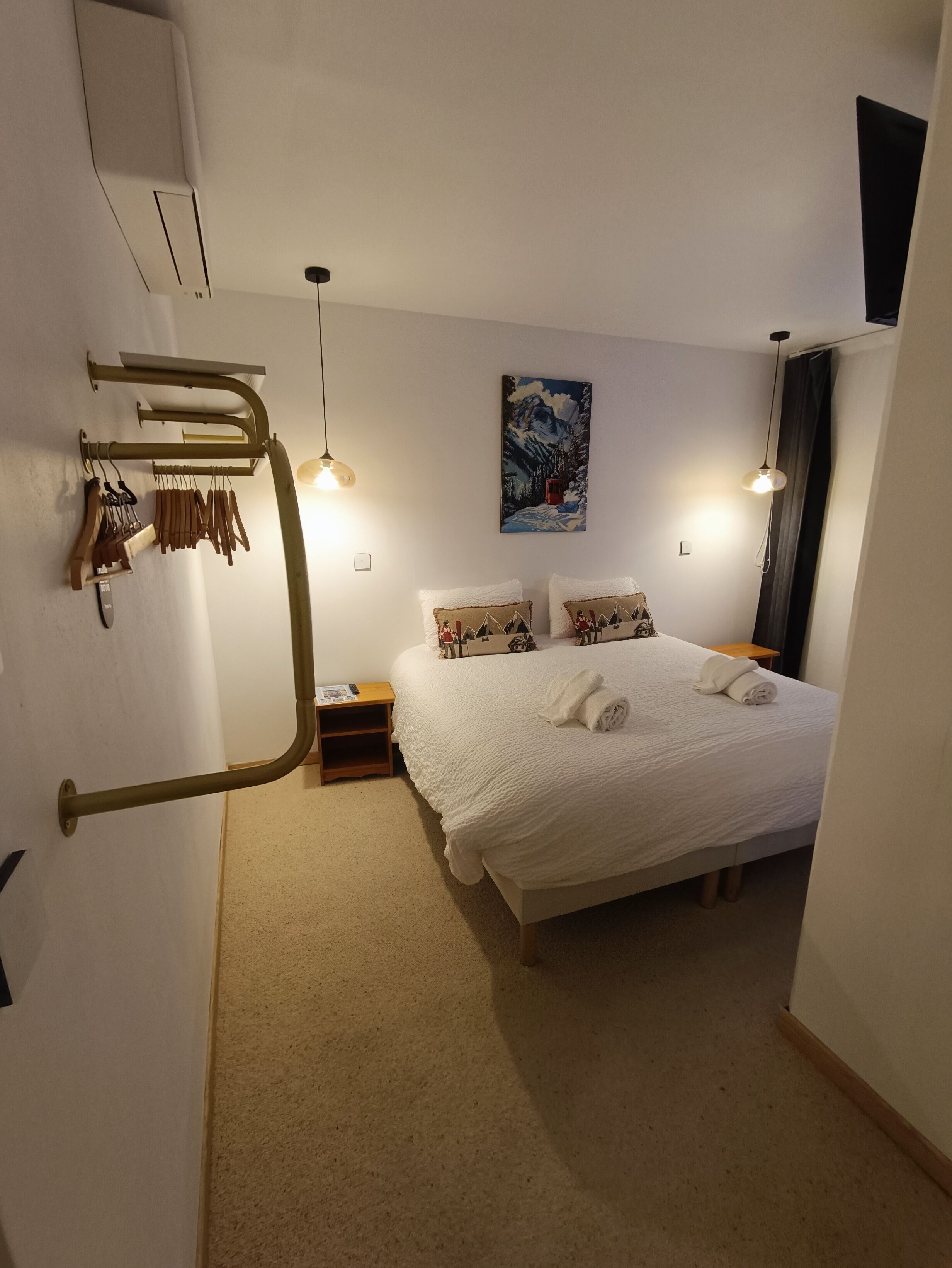 Um quarto com uma cama, um quadro na parede e um lustre.
