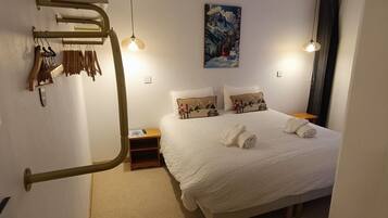 Um quarto com uma cama, um quadro na parede e um lustre.