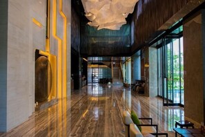 Um hall amplo com teto alto, escadaria e grandes janelas.