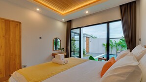 Quarto de hotel moderno com uma cama grande, um guarda-roupa de madeira, uma mesinha com uma planta e vista para o exterior.
