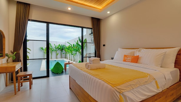 Quarto moderno com uma cama grande, uma escrivaninha e vista para uma piscina e áreas verdes.