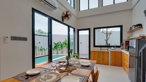 Cozinha moderna com área de refeições, janelas amplas e vista para uma piscina.