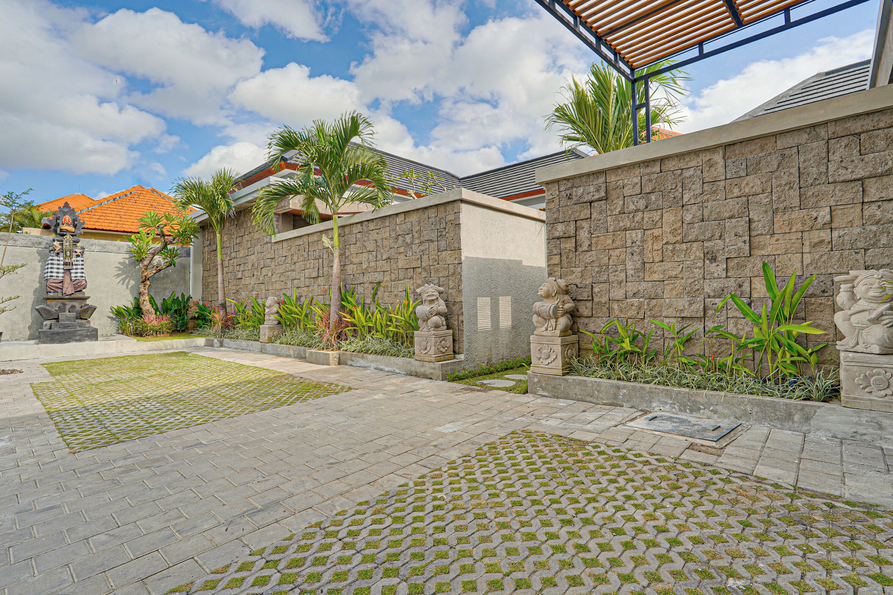 Um pátio com paredes de pedra, estátuas e piso de azulejos.
