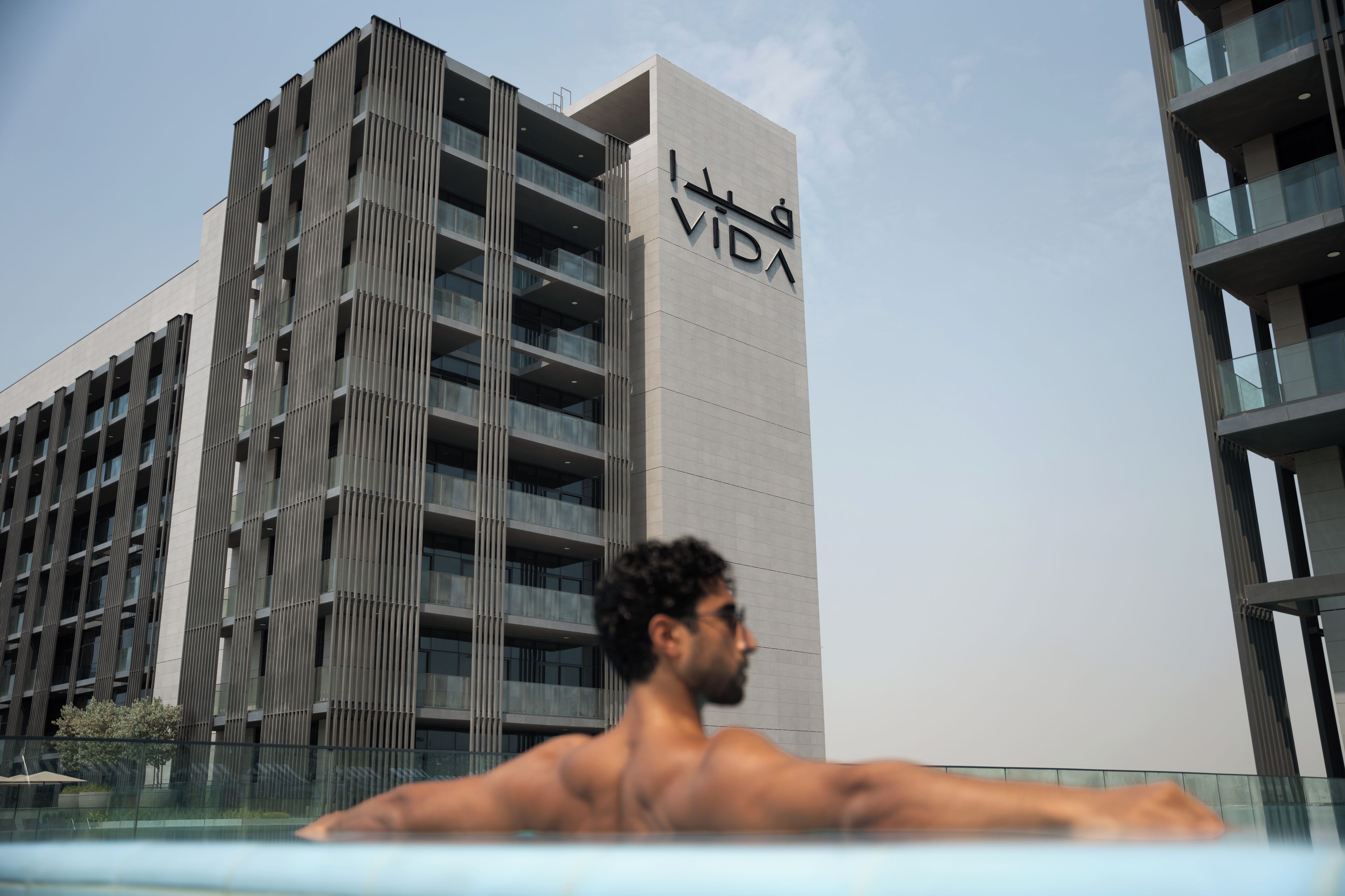 Um edifício moderno com um destaque para a placa 'VIDA', apresentando um design arquitetônico único com linhas verticais e varandas.