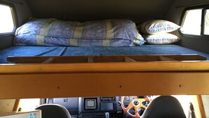 Interior compacto de uma RV com cama de beliche, volante e painel.