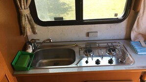 Uma cozinha compacta equipada com pia, fogão a gás e escorredor de louça verde.