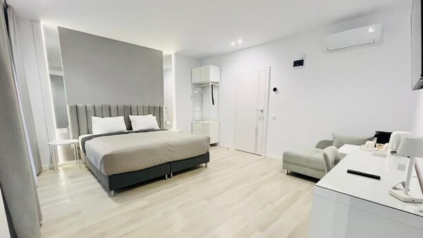 Quarto de hotel moderno com cama, mesa de cabeceira e escrivaninha com abajur.