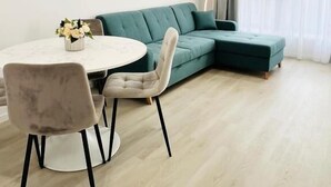 Uma sala de estar moderna com um sofá verde, uma mesa de jantar redonda e duas cadeiras.