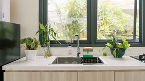 Uma cozinha com pia, janela e plantas em vasos.