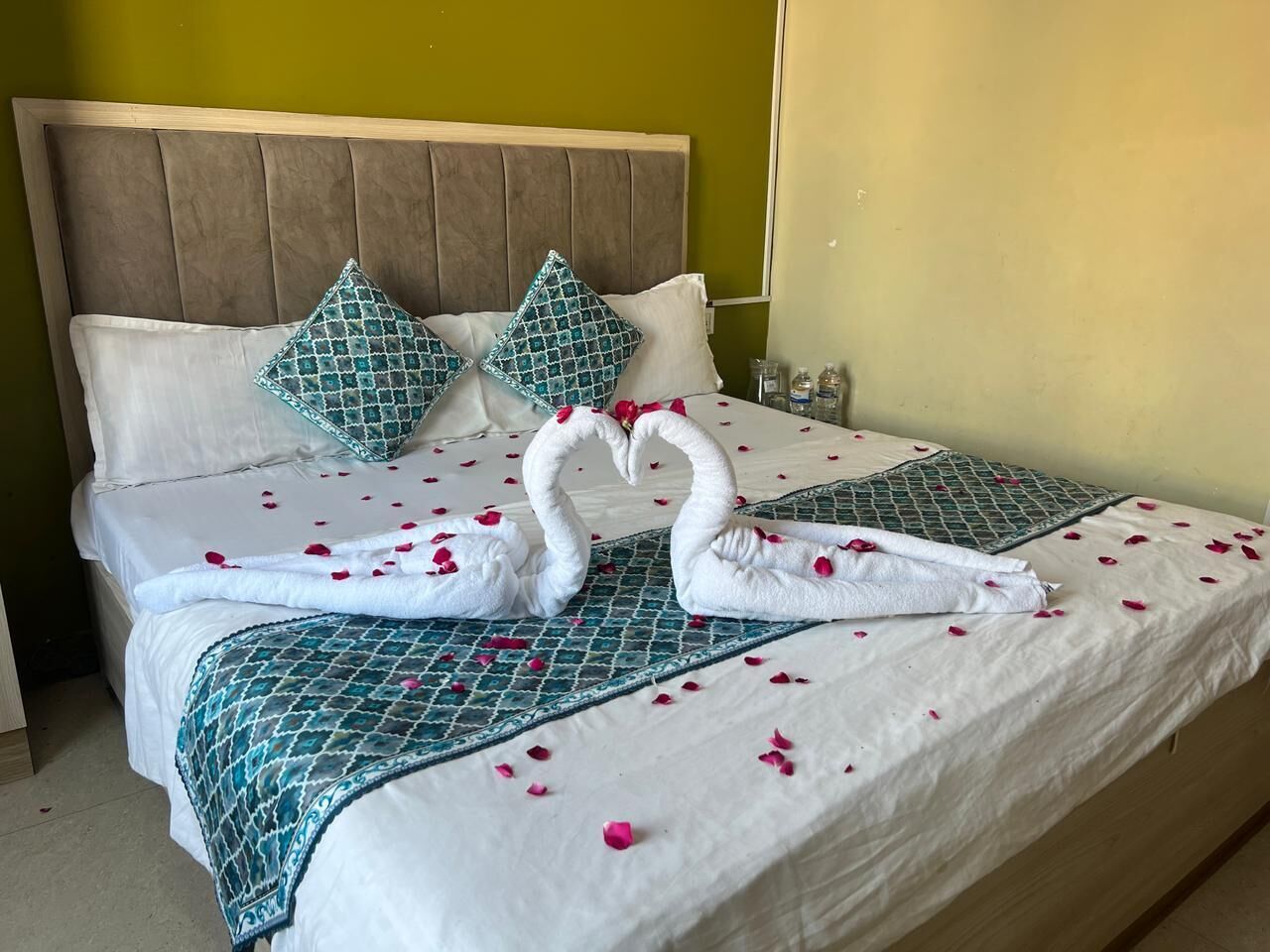 Cama bem arrumada com colcha estampada, almofadas e duas toalhas em formato de cisne.