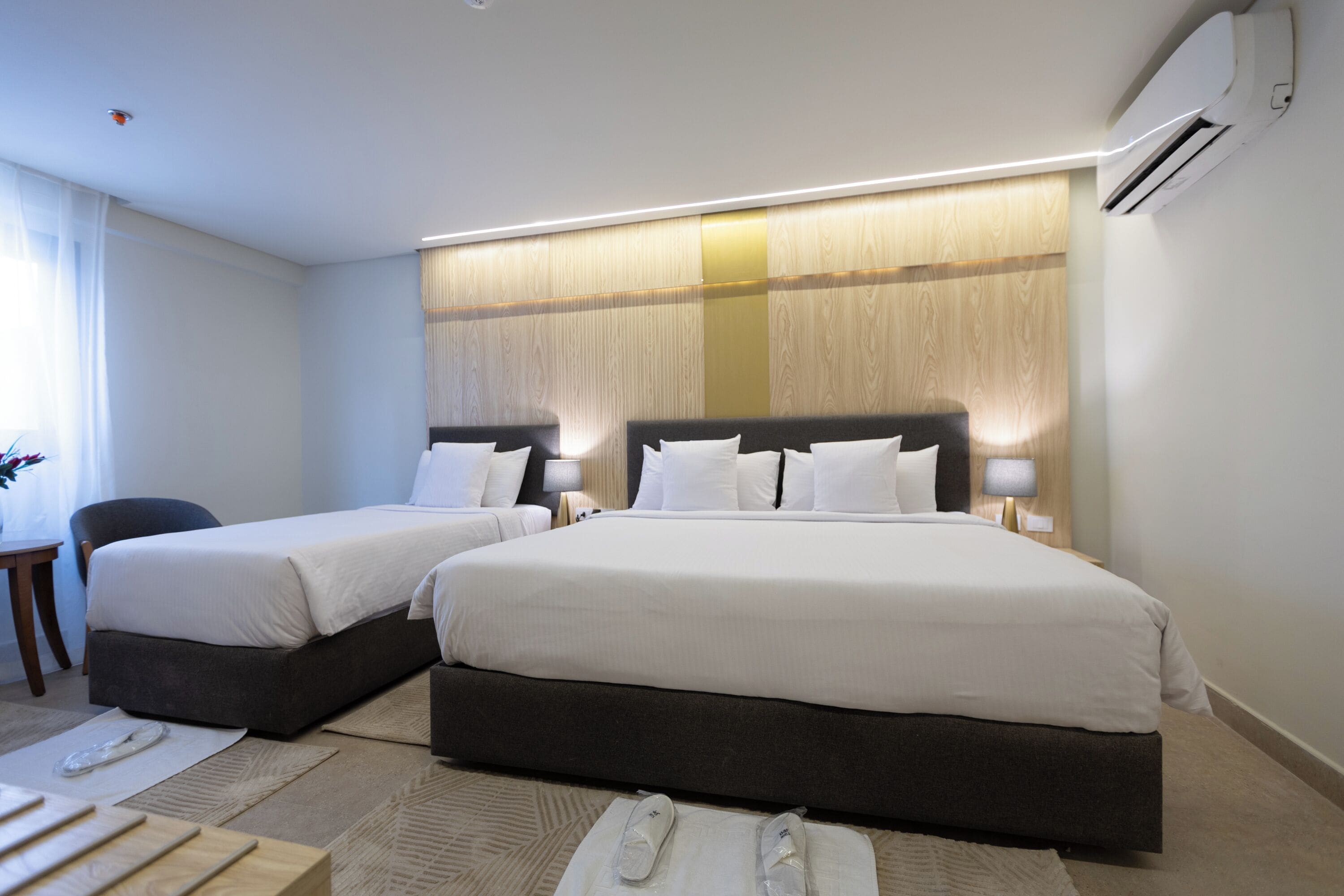 Quarto de hotel com duas camas, uma escrivaninha e uma cadeira.