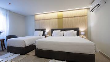 Quarto de hotel com duas camas, uma escrivaninha e uma cadeira.