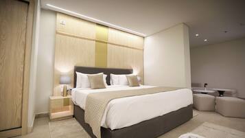 Quarto de hotel moderno com uma cama grande, mesas de cabeceira, um criado-mudo, uma luminária e uma pequena mesa com um vaso.