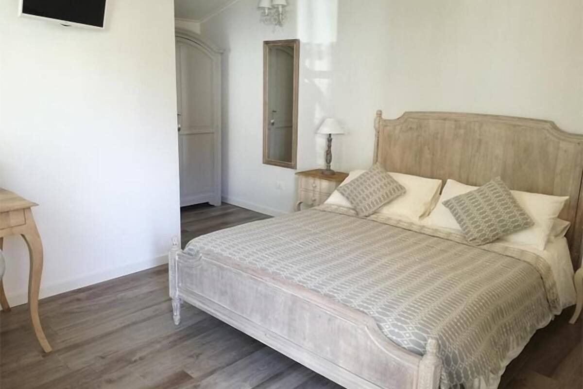 Quarto com cama de madeira, mesa de cabeceira e luminária.