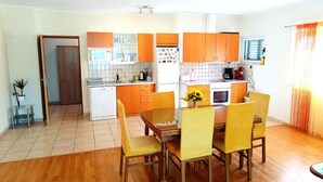 Cozinha compacta com armários de madeira, uma mesa de jantar com quatro cadeiras e uma pequena mesa lateral.