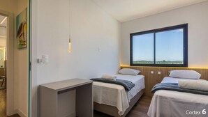 Quarto com duas camas, uma escrivaninha, janela com vista e um quadro na parede.