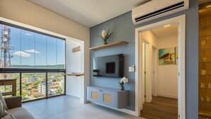 Sala de estar moderna com uma janela grande, televisão na parede e um armário de madeira.