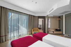 Quarto de hotel com duas camas, uma cadeira, uma escrivaninha e um guarda-roupa.